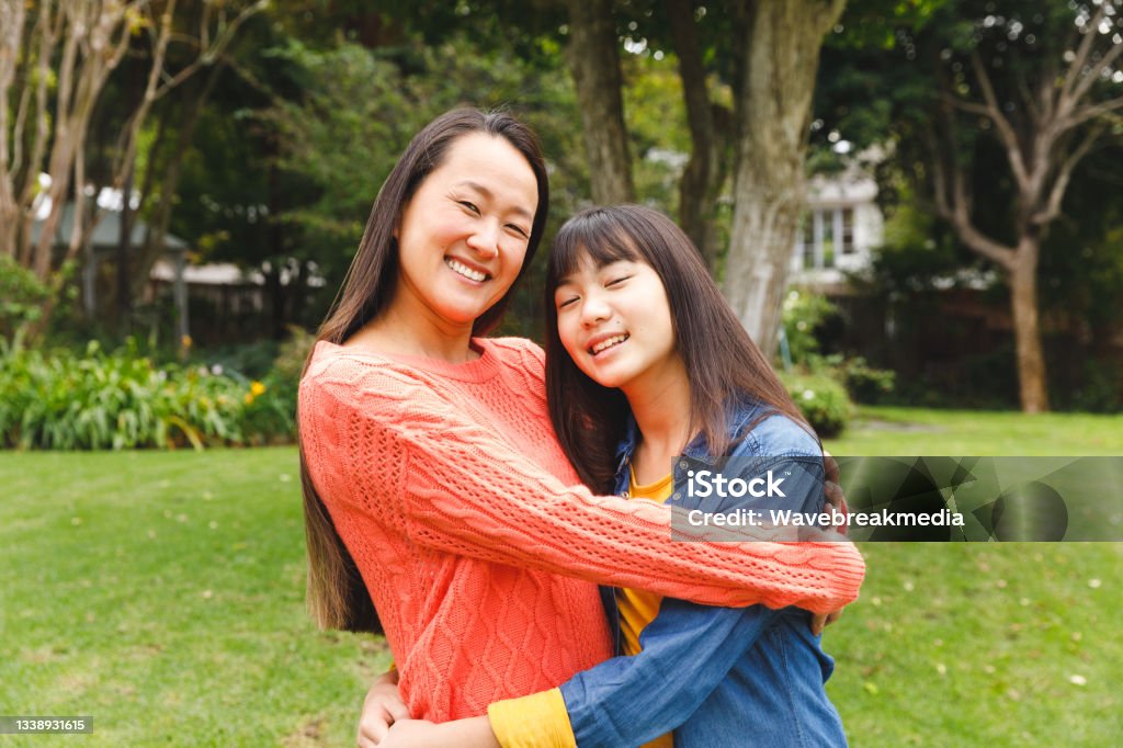 Portrait Of Happy Asian Mother Embracing Her Daughter And Smiling