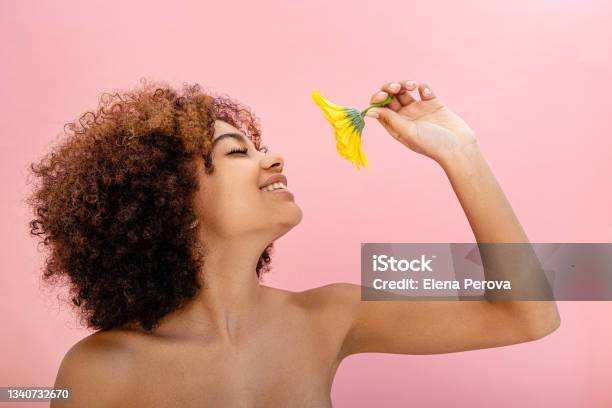 Portrait Of A Beautiful Darkskinned Young Woman Sniffing A Yellow