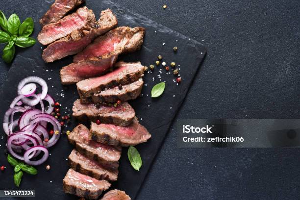 Irisan Daging Sapi Langka Di Papan Batu Dengan Bawang Dan Kemangi Steak