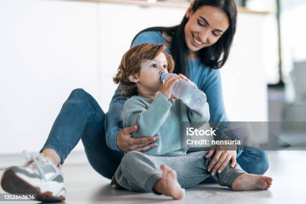 Ibu Muda Yang Cantik Menatap Putranya Sambil Minum Air Dari Botol