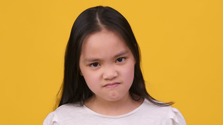 Studio Portrait Of Shy Young Girl Smiling And Laughing Against Yellow ... Studio Portrait Of Shy Young Girl Smiling And Laughing Against Yellow ...