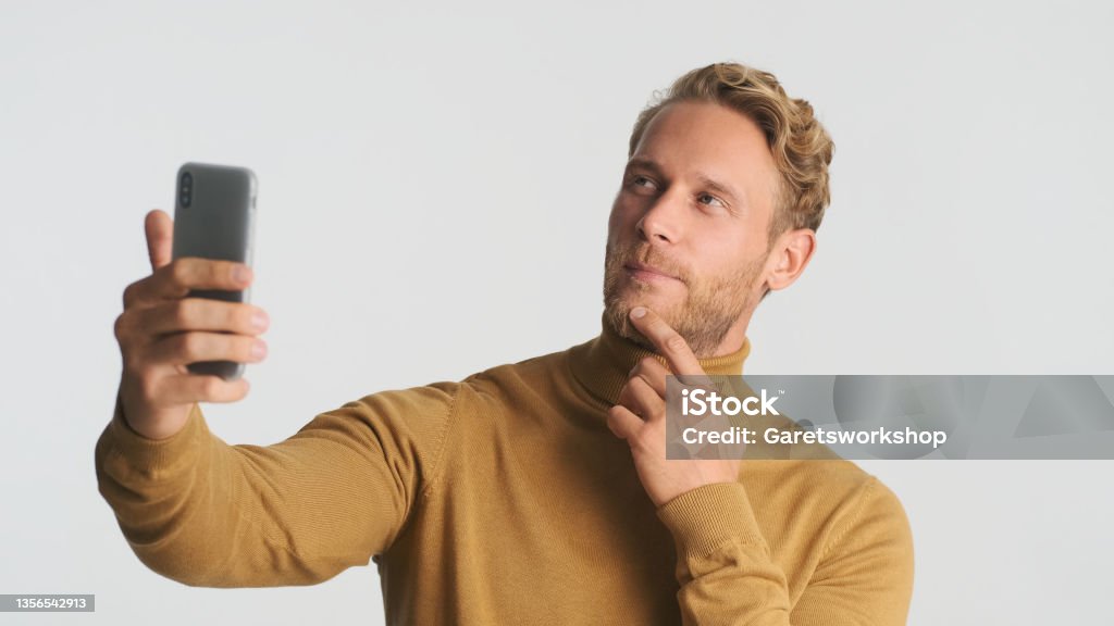 Attractive Blond Bearded Man In Turtleneck Thinking While Talking With