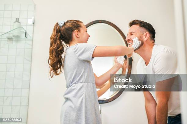 Shot Of A Father Teaching His Daughter How To Shave His Face At Home