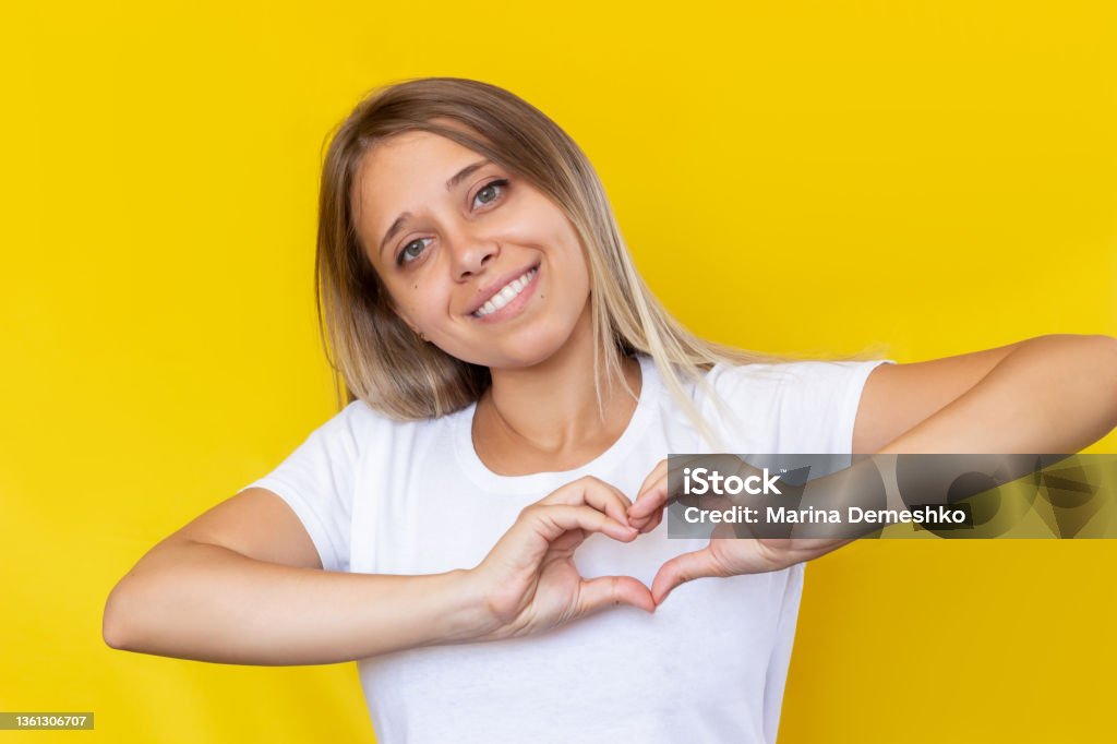 A Young Blonde Woman Forming A Heart Shape With Her Hands On A Color