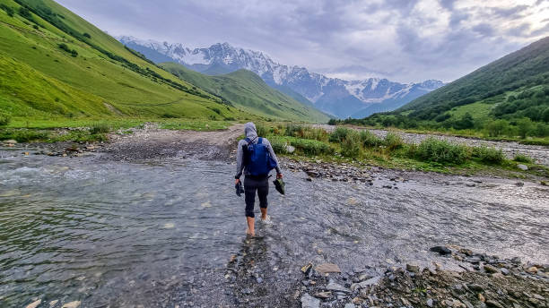 Free Stock Photo of Man Walking Across River Next to Mountain ...