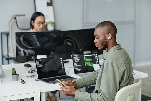 Young African American Office Worker In Earphones Scrolling In Mobile ... Young African American Office Worker In Earphones Scrolling In Mobile ...