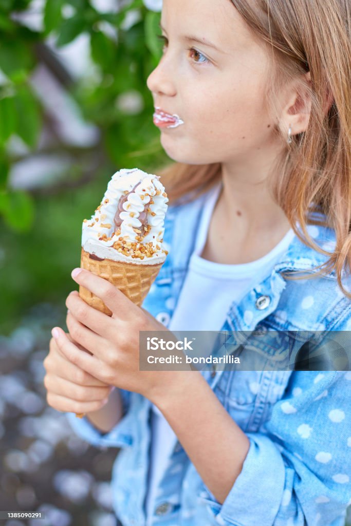 Cute Girl Liccking And Eating Italian Ice Cream Cone While Resting In Park On Summer Day Stock