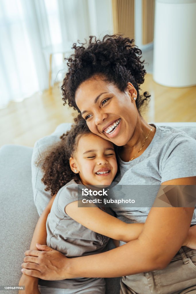 Closeup African Daughter Embracing Mother Sitting On Couch At Home