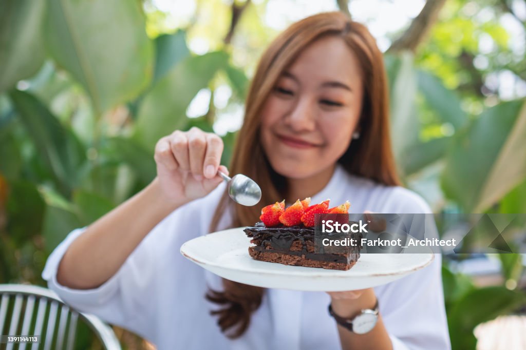 Portrait Image Of A Beautiful Young Asian Woman Holding And Eating A
