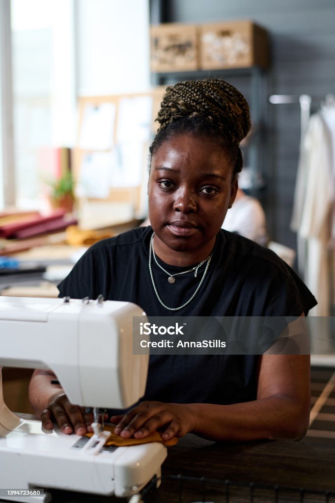 Young Black Woman Looking At Camera While Using Electric Sewing Machine