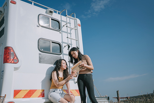 Asian Chinese Lesbian Couple Reading Digital Tablet At The Back Of
