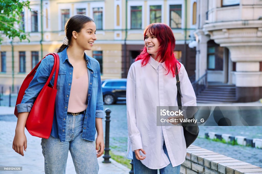 Two Walking Talking Laughing Teenage Girls Walking Down The City Street