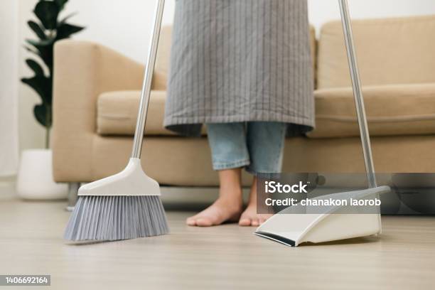 Close Up Housewife Using Broom And Dustpan Wearing An Apron To Clean