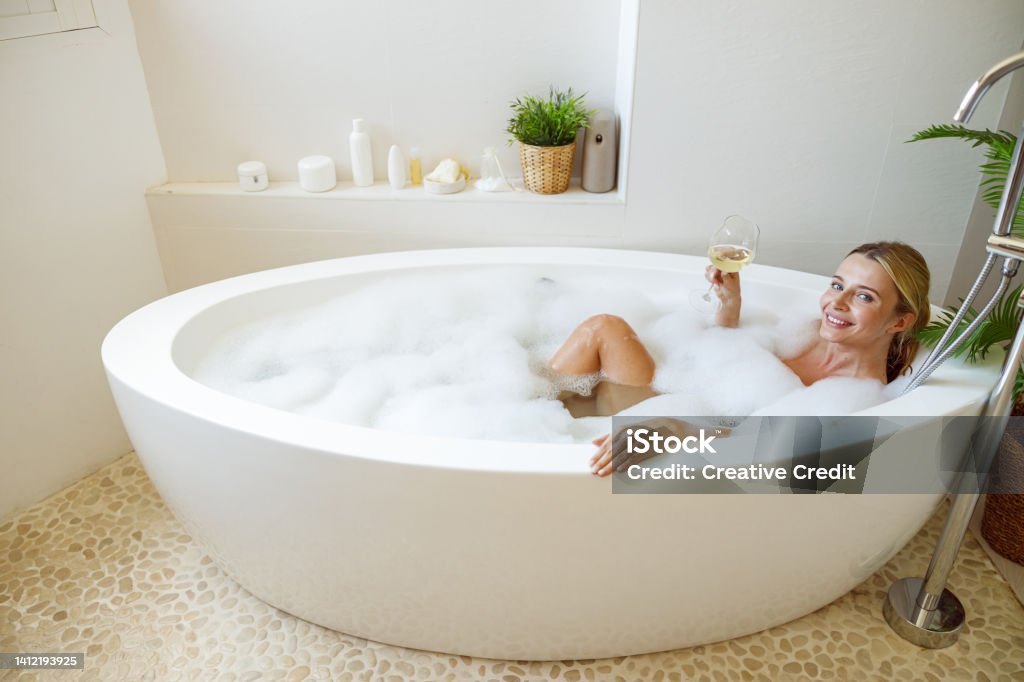 Blonde Beautiful Young Woman Lying In Bathtub With Foam And Holding