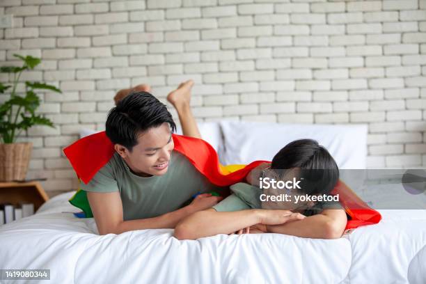 Happy Asian Gay Couple Talking Together And Relaxing At Home On Bed