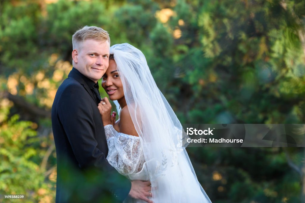 Portrait Of Young Beautiful Interracial Newlyweds On Green Foliage