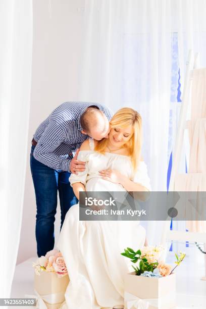 Photo Libre De Droit De Un Mari Embrasse Doucement Sa Femme Enceinte Qui Sassoit Sur Une Chaise