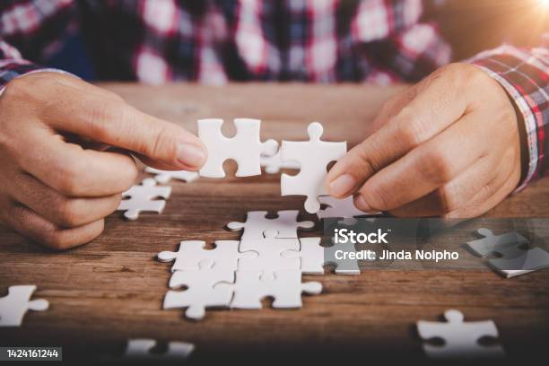 Tangan Memegang Potongan Puzzle Jigsaw Di Atas Latar Belakang Meja Kayu