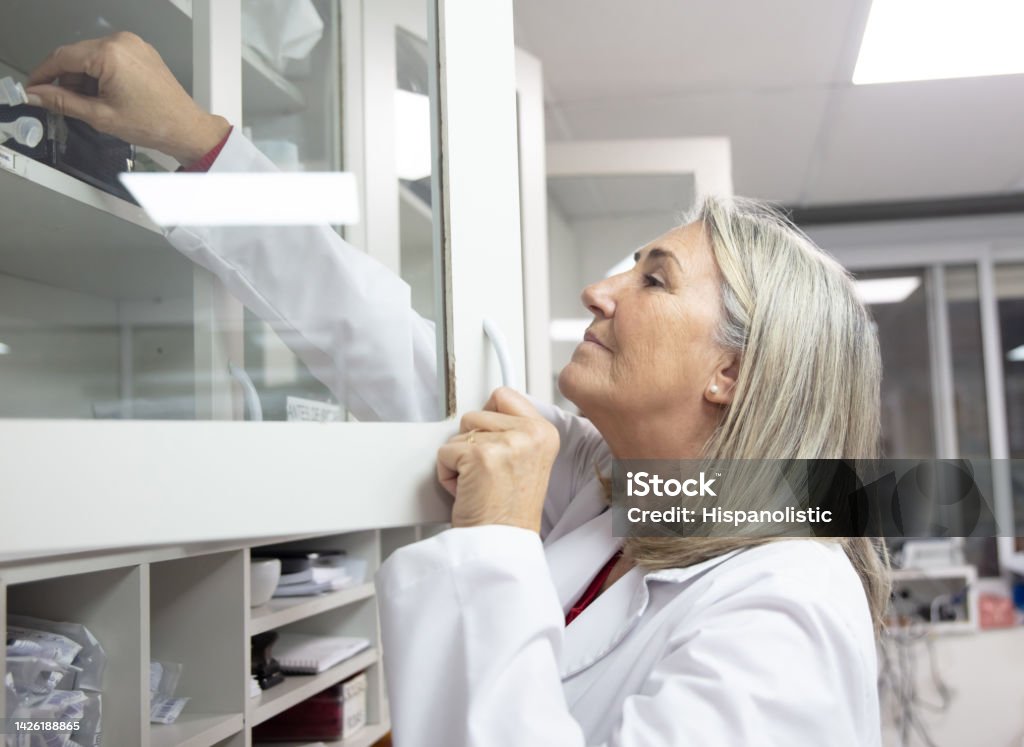 Senior Female Doctor Grabbing Something From The Nurses Station Before ... Senior Female Doctor Grabbing Something From The Nurses Station Before ...
