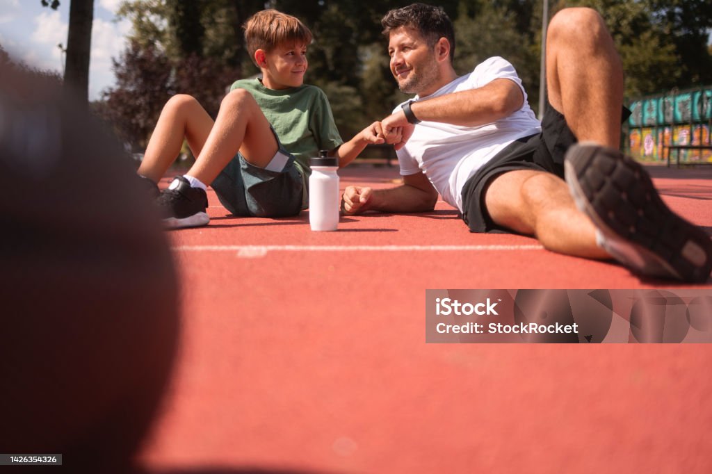 Foto De Alegre Preteen Menino Punho Batendo Com Seu Pai Na Quadra De Basquete E Mais Fotos De