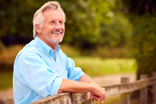 Portrait Of Smiling Casually Dressed Mature Or Senior Man Leaning On