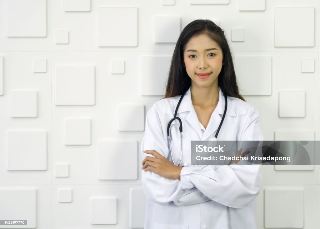Dokter Muda Asia Dengan Gaun Putih Dan Stetoskop Berdiri Dengan Salib ... Dokter Muda Asia Dengan Gaun Putih Dan Stetoskop Berdiri Dengan Salib ...