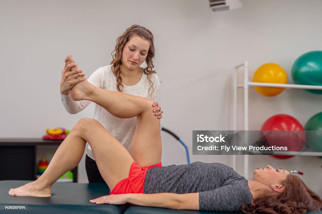 Physical Therapist Stretching Out Her Female Patient On A Massage Table