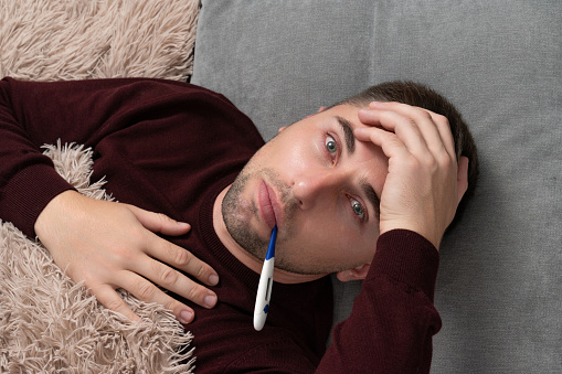A Man Takes His Temperature And Holds His Head With His Hand Because Of ... A Man Takes His Temperature And Holds His Head With His Hand Because Of ...