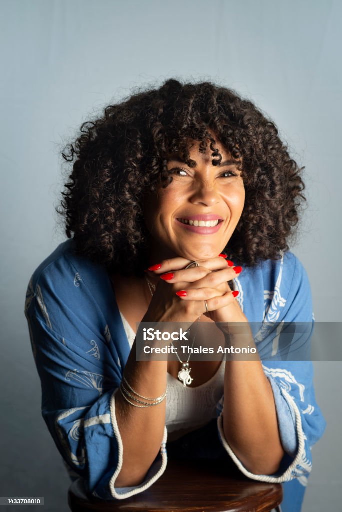 Portrait Of Smiling Beautiful Curly Hair Model Against Light Background