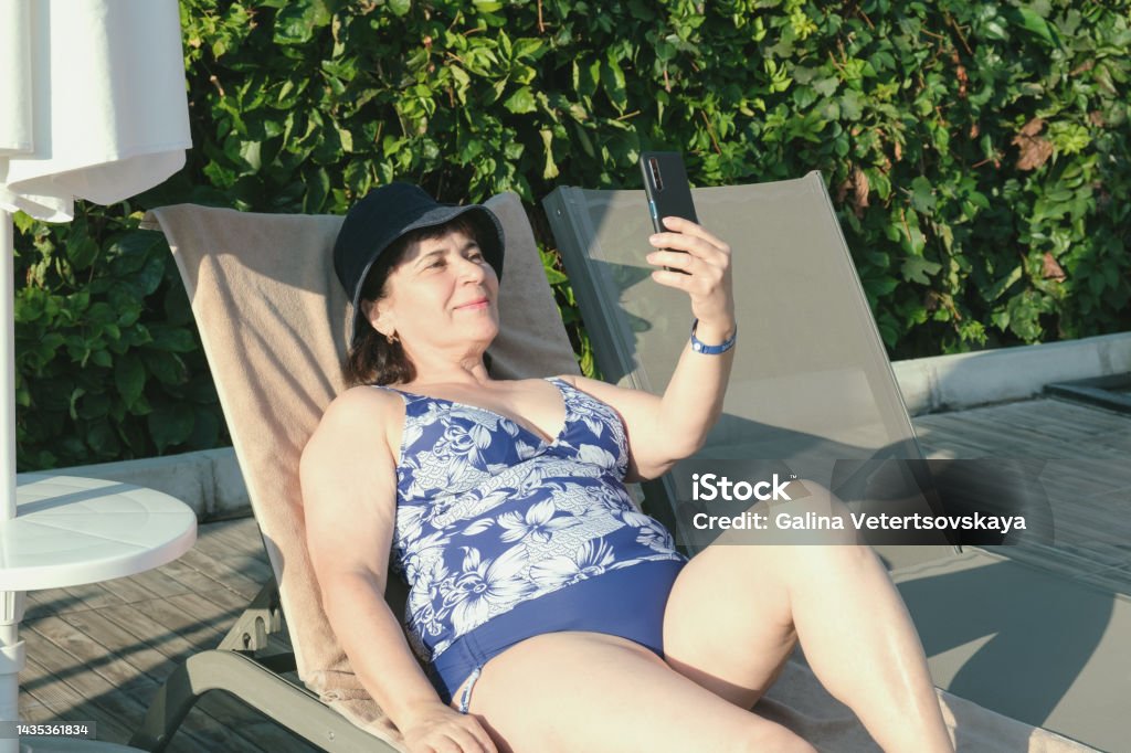 Photo Libre De Droit De Une Femme Âgée En Maillot De Bain Sur Une Chaise Longue Au Bord De La