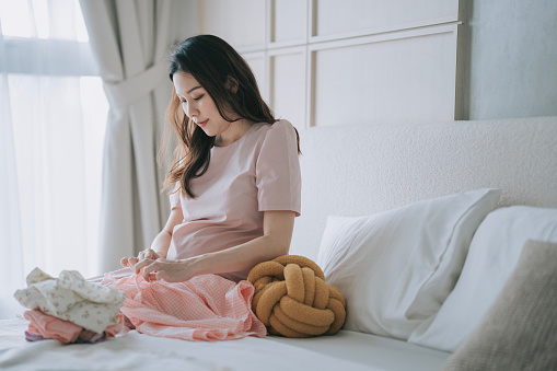 행복 한 아시아 중국 임신 한 여자 침대에 앉아 아기 옷을 접는 새로 태어날 준비 30 34세에 대한 스톡 사진 및 기타 이미지
