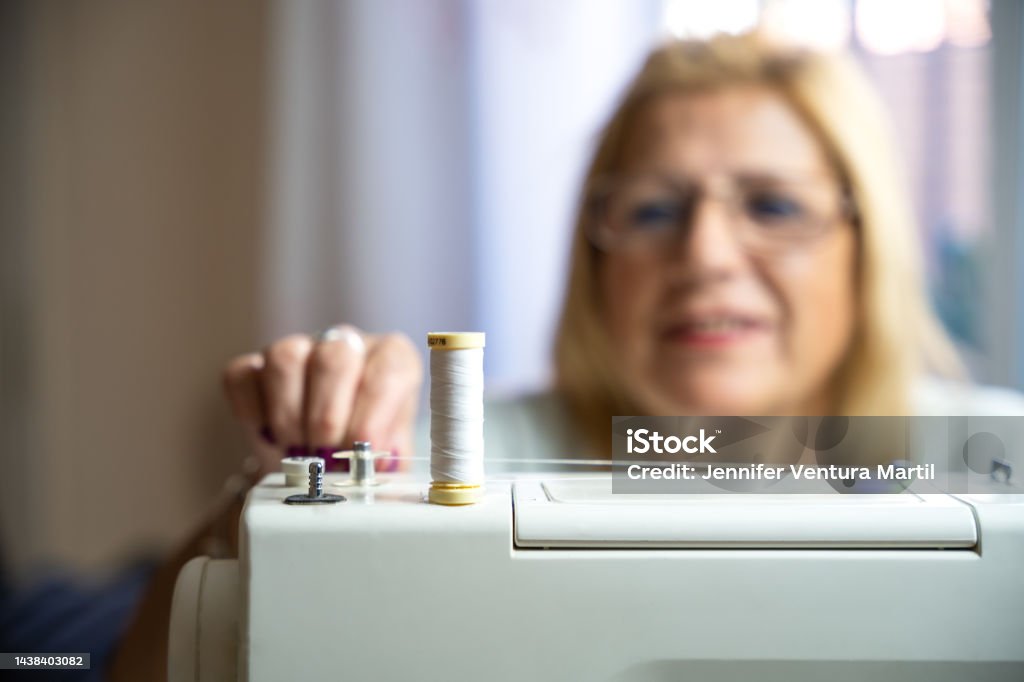 Woman Seamstress With Glasses Sitting While Preparing The Thread Of Her