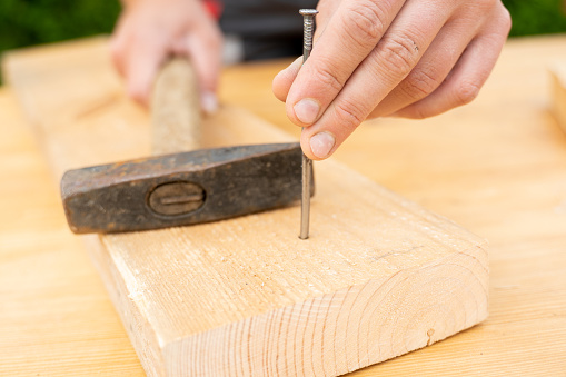 Dari Dekat Pria Yang Memalu Paku Ke Papan Kayu Menggunakan Palu Dan