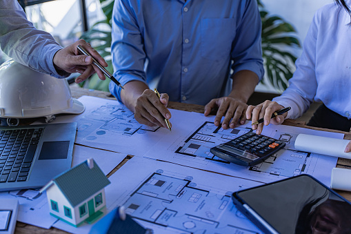 Architects And Engineers Point To Buildings On Blueprints And Use