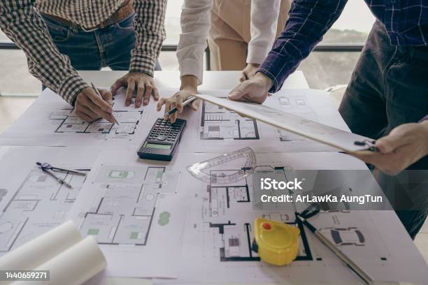 Architects And Engineers Point To Buildings On Blueprints And Use