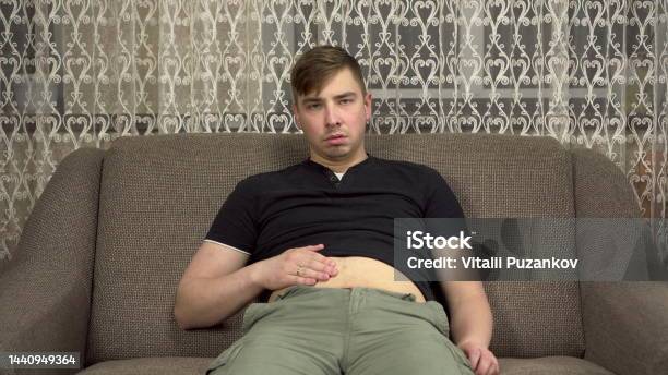 A Young Man Touches His Fat Belly And Then Cries The Man On The Couch Slaps On His Stomach