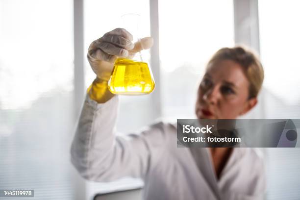Ilmuwan Wanita Memegang Termos Erlenmeyer Dengan Cairan Kuning Dan