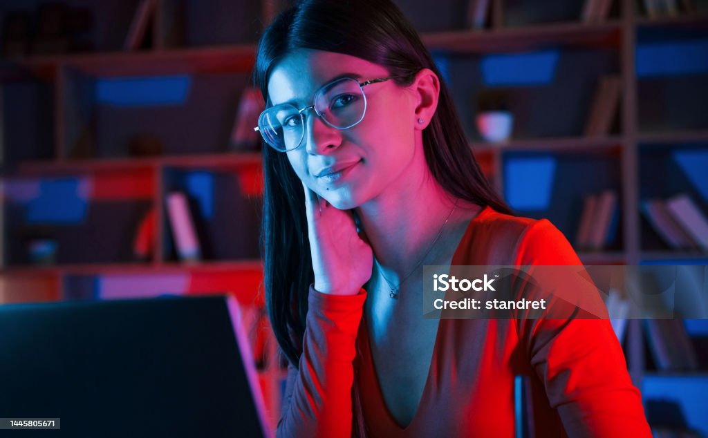 Beautiful Woman In Glasses And Red Wear Is Sitting By The Laptop In