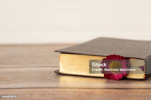 Buku Alkitab Tertutup Dengan Halaman Emas Dan Bunga Di Atas Meja Kayu