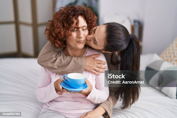 Two Women Mother And Daughter Drinking Coffee Sitting On Bed Stock