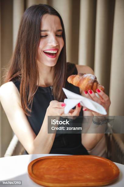 Wanita Muda Yang Cantik Makan Croissant Dan Tampak Bahagia Di Restoran