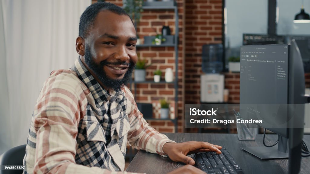 Software Developer Typing Programming Code On Computer Keyboard Turning Head And Smiling Stock