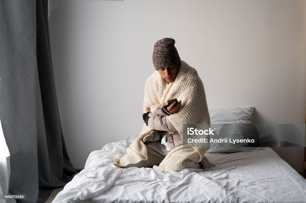 Young Man Warmly Dressed Is Feeling Cold Covered With Warm Blanket