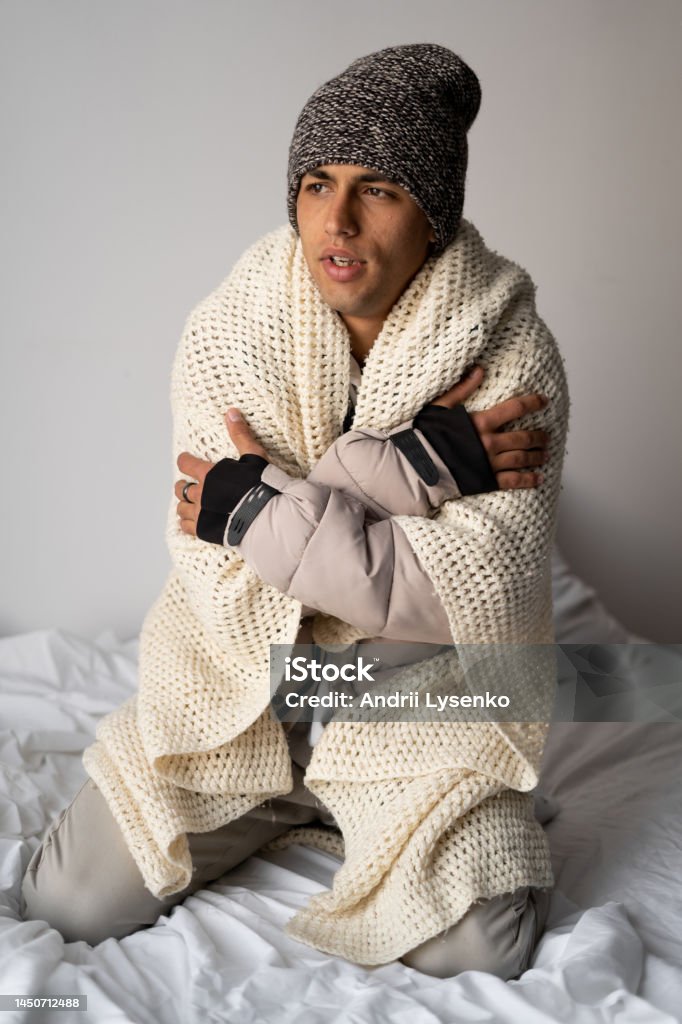 Young Man Warmly Dressed Is Feeling Cold Covered With Warm Blanket