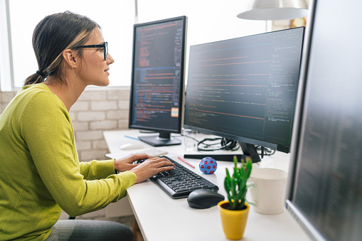 Young Female Programmer Standing On Her Desk Coding On The Computer Pc