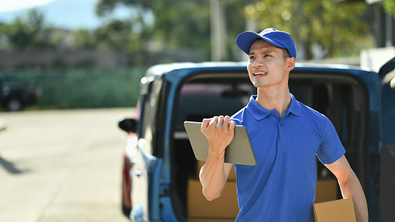 Portrait Of Delivery Man Wearing Blue Uniform With Cardboard In Hands