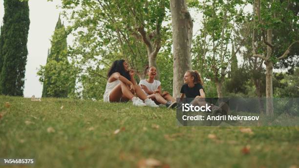Tiga Teman Perempuan Praremaja Duduk Di Rumput Di Taman Dan Berbicara ... Tiga Teman Perempuan Praremaja Duduk Di Rumput Di Taman Dan Berbicara ...