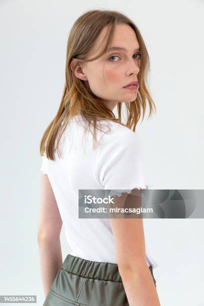 A Freckled Blonde Girl Against A White Background Wearing A White