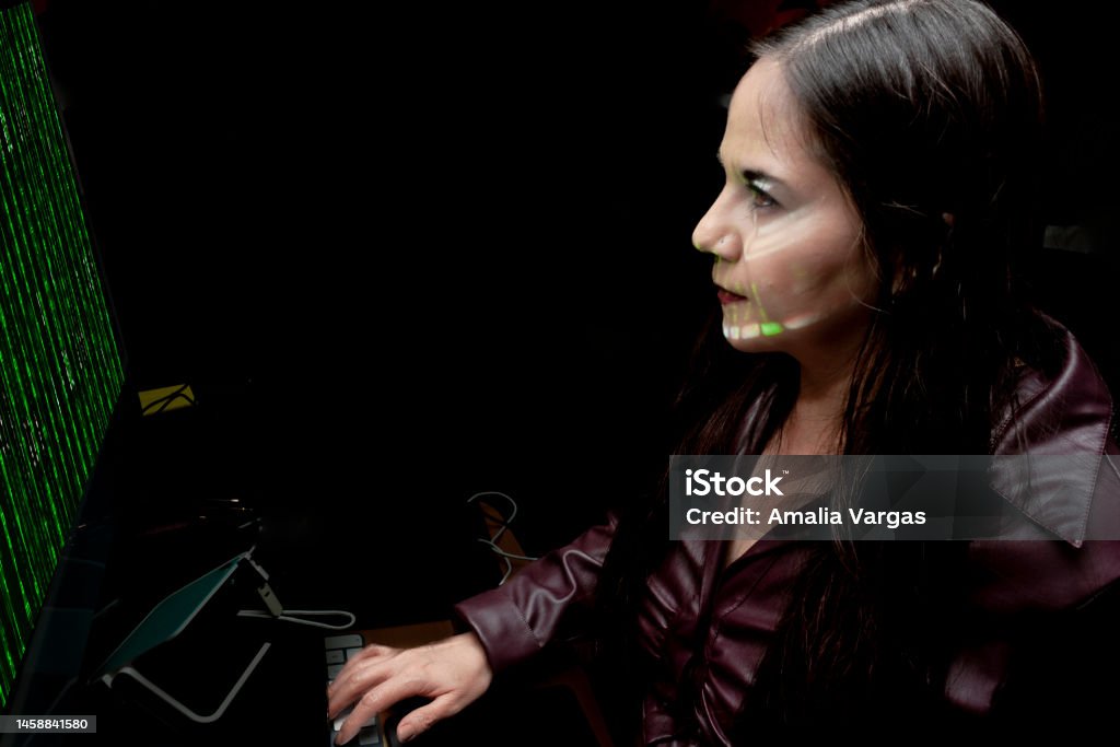 Woman Writes Programming Languages In Development Code In Front Of Computer Seated At Work Desk