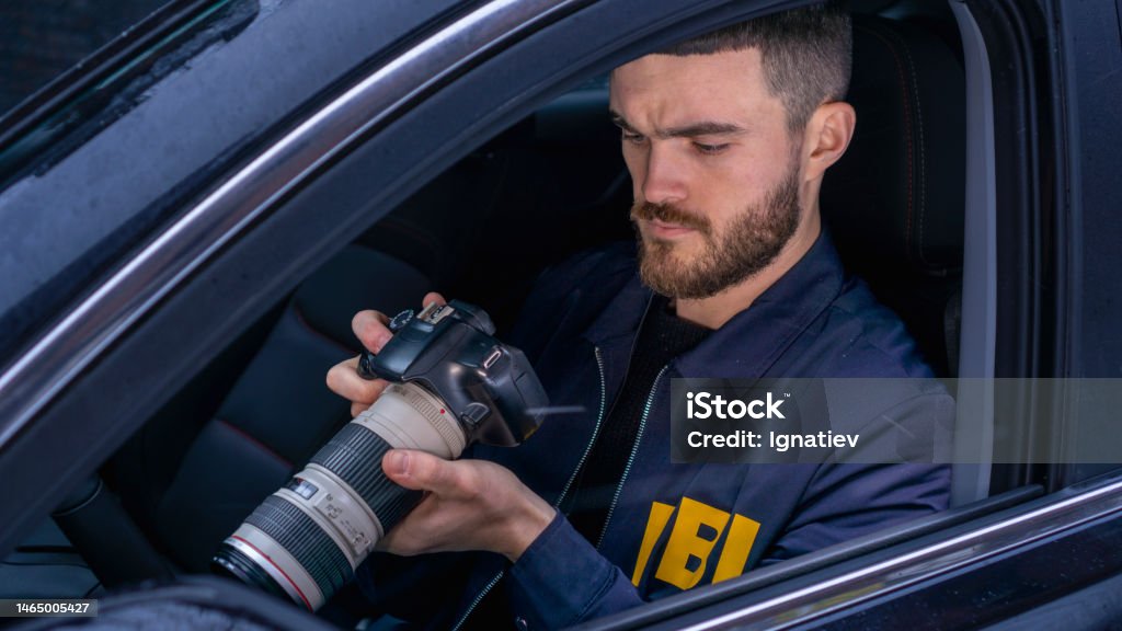 Young Handsome Fbi Agent In A Car With Camera During Surveillance An